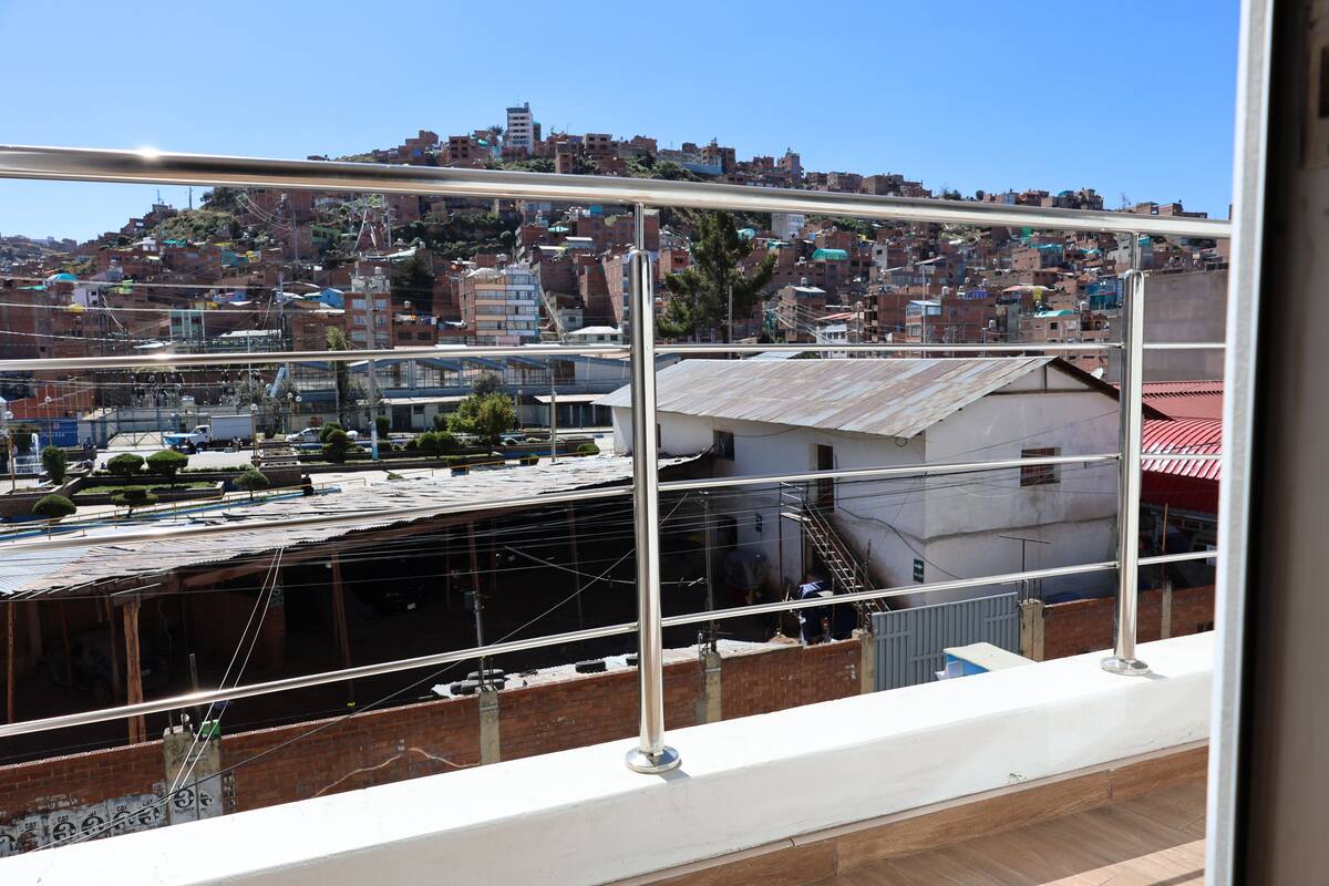 Vista de uma varanda com vista para uma área urbana densamente povoada, com edifícios e infraestrutura.