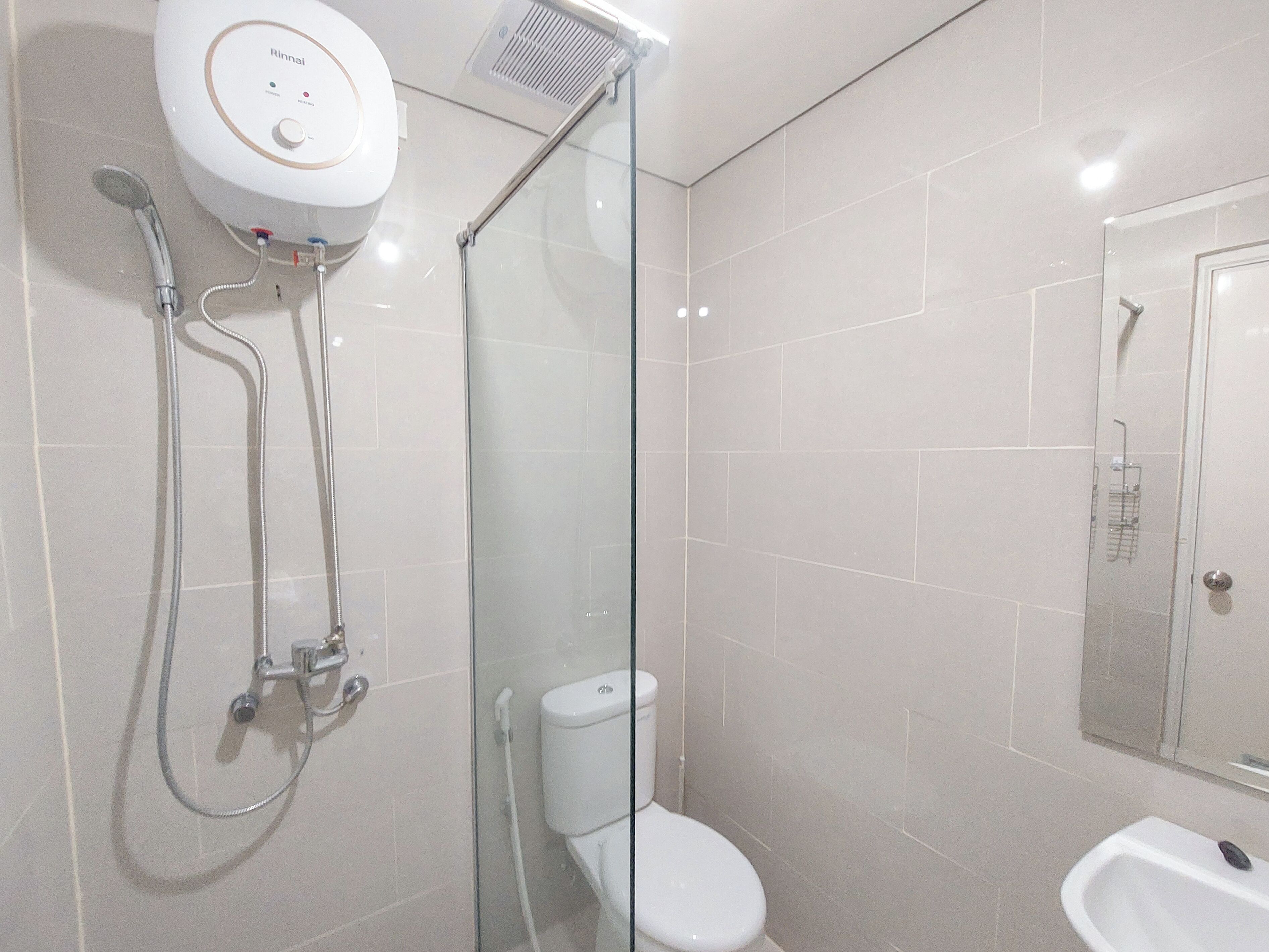 Um banheiro moderno com chuveiro em cabine de vidro, vaso sanitário e pia.