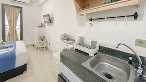 Cozinha moderna com pia, bancada e prateleira de madeira acima.