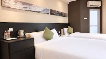 Quarto de hotel com duas camas, mesa de cabeceira, cafeteira e aparelho de ar condicionado.