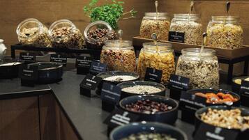 Diversos alimentos expostos em potes de vidro com etiquetas, dispostos sobre um balcão.