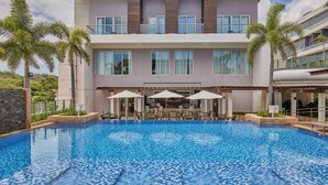 Um hotel com piscina, área de estar externa e palmeiras.
