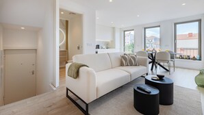 Uma sala de estar moderna com um sofá branco, uma mesa de centro e uma área de refeições com cadeiras e uma mesa.