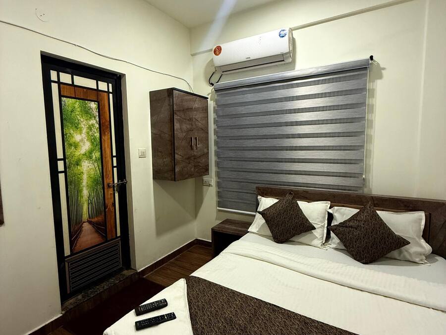 Quarto de hotel com cama, mesa de cabeceira, guarda-roupa, ar condicionado e uma porta com vista para uma trilha na floresta.