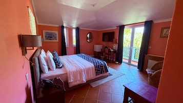 Quarto com cama, escrivaninha e cadeira. Possui janela e porta com acesso a uma varanda.