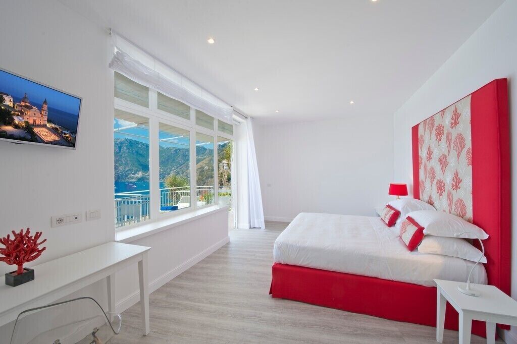Quarto de hotel moderno com uma cama grande, uma escrivaninha e uma TV na parede.