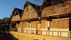 Um edifício tradicional com vários níveis, com telhados de palha e uma varanda com grades.