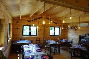 Uma cabana de madeira com área de jantar montada para várias pessoas, com mesas, pratos, copos e talheres.