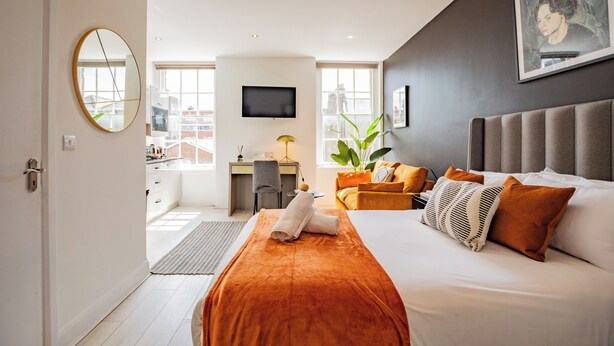 Quarto de hotel moderno com cama, escrivaninha e televisão.