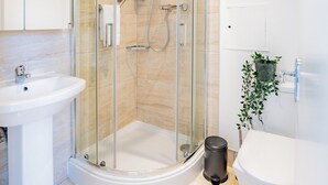 Um banheiro moderno com chuveiro envidraçado, pia de pedestal e vaso sanitário.