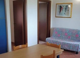 Um quarto com uma mesa de madeira, um sofá estampado e uma moldura na parede.