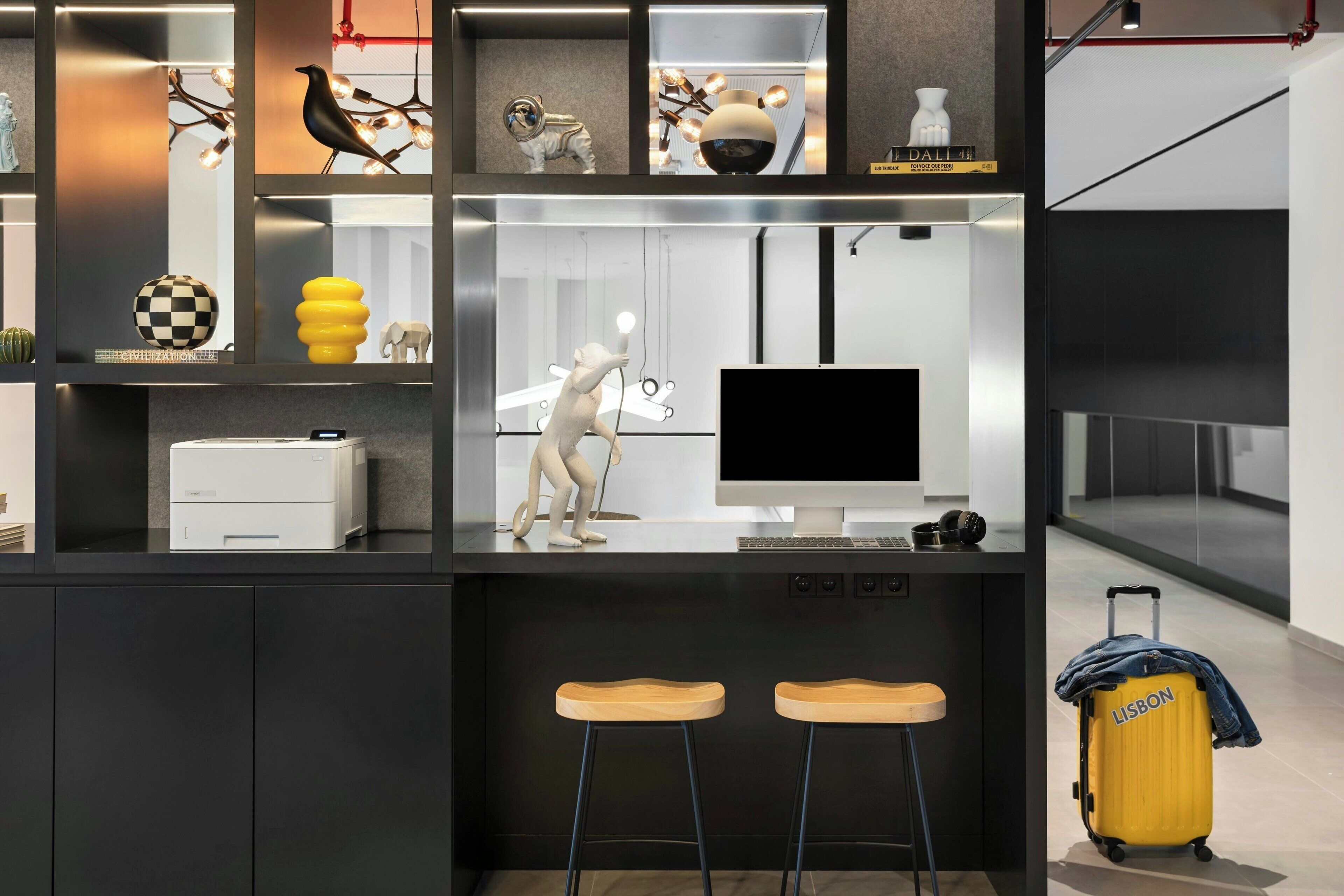 Uma cozinha moderna com ilha central, banquetas, uma televisão e uma mala.