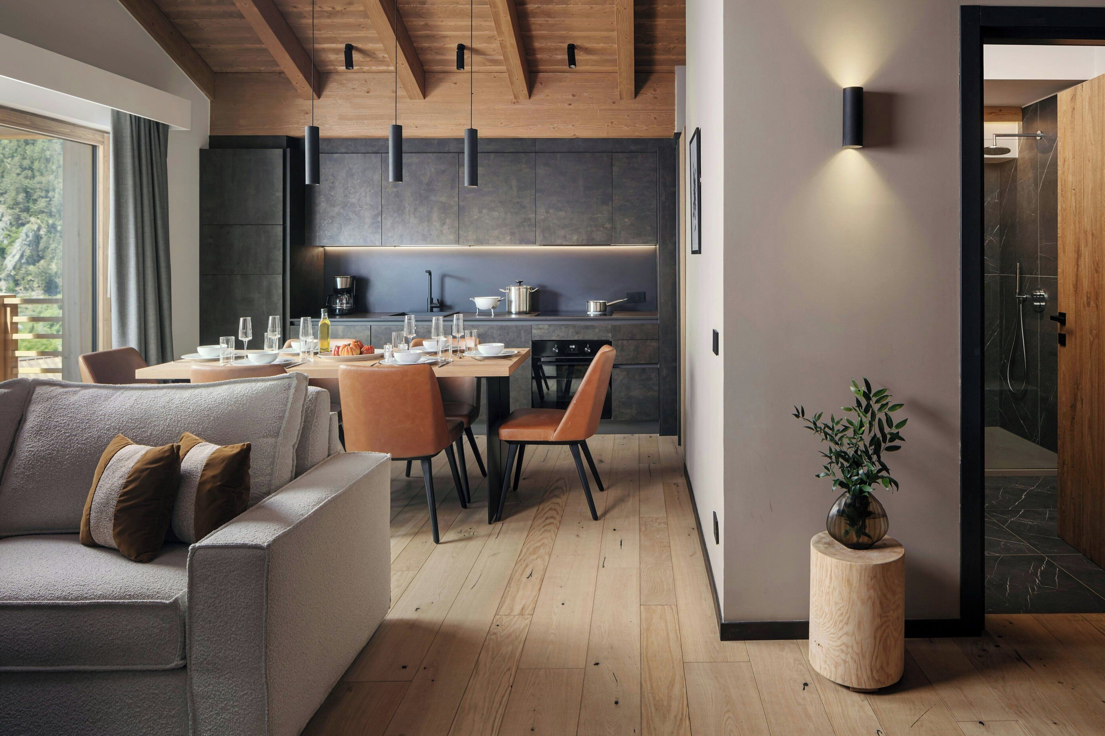 Um interior moderno com área de jantar, cozinha e sala de estar com sofá e planta.