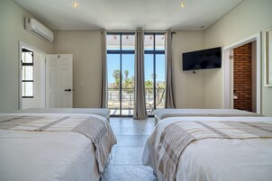 Quarto de hotel com duas camas, televisão e varanda com vista.