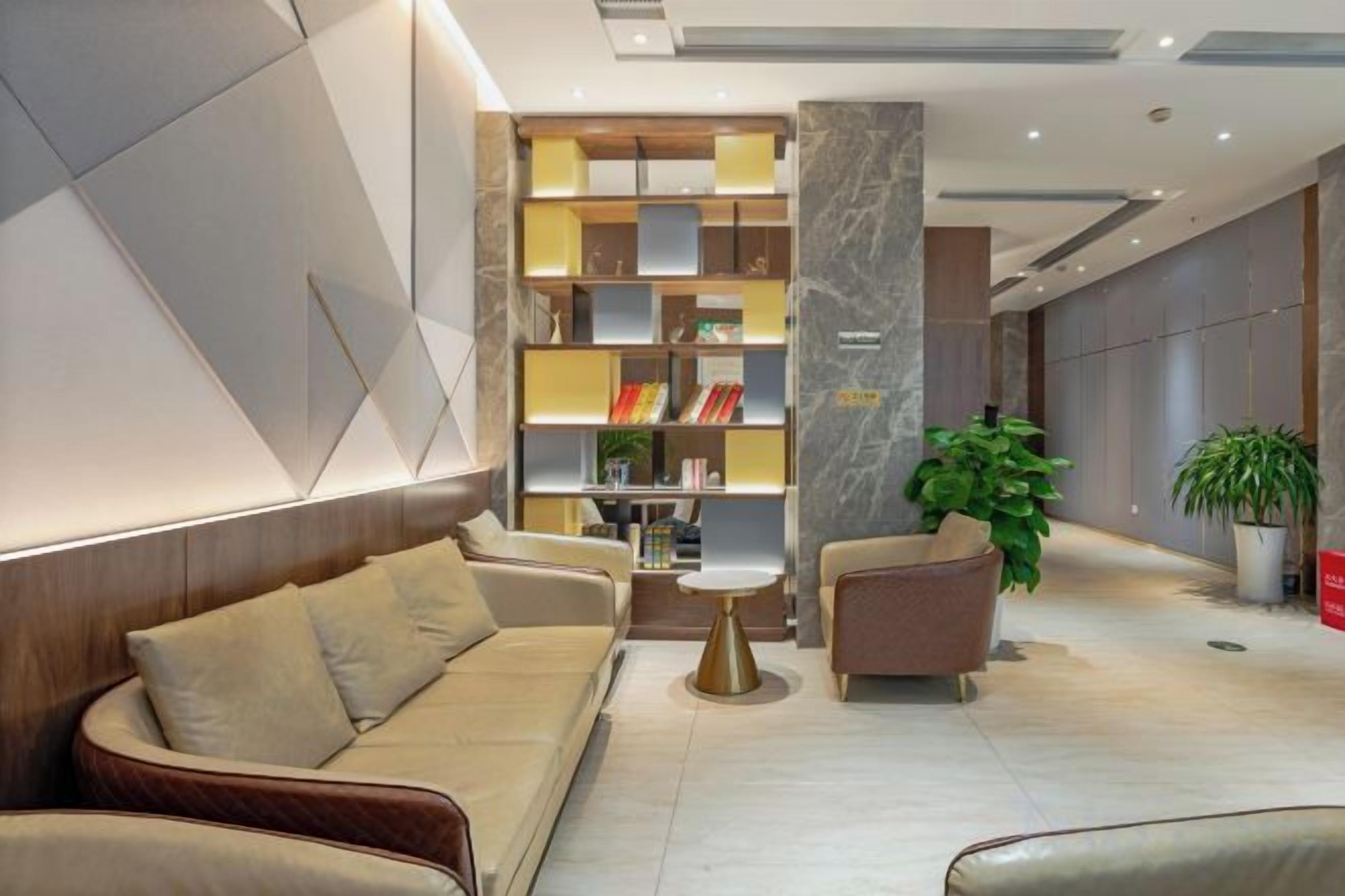 Um hall moderno com um sofá, poltronas, uma mesa de centro, uma estante de livros e uma planta em vaso.