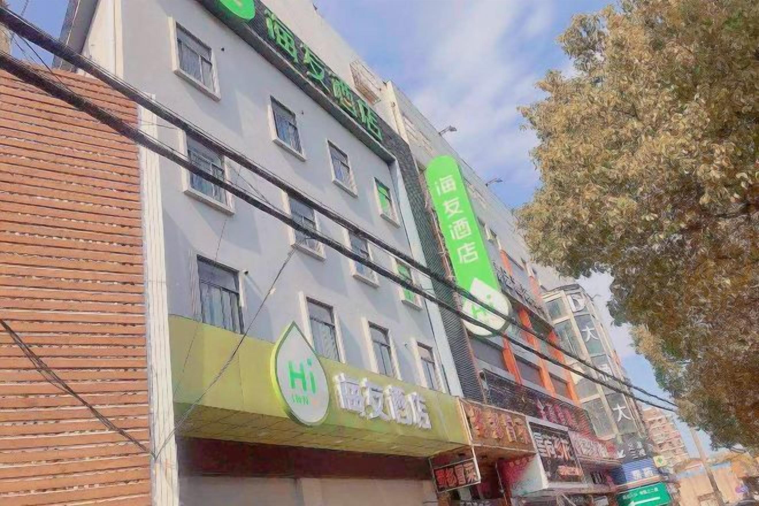 Um edifício de vários andares com uma placa verde indicando um estabelecimento no andar térreo.