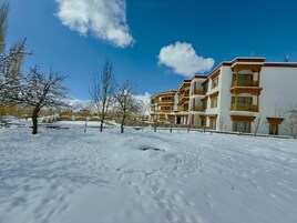 Pátio coberto de neve com um edifício com arquitetura tradicional e varandas.