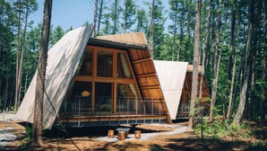 Uma cabana com telhado inclinado, janelas grandes e um deck.