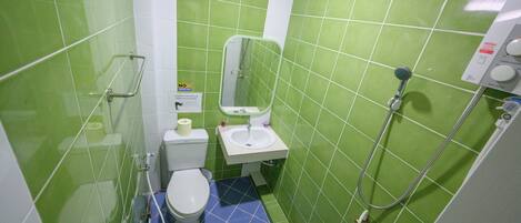 Um banheiro pequeno com azulejos verdes, vaso sanitário branco, pia, espelho e chuveiro com chuveiro manual.