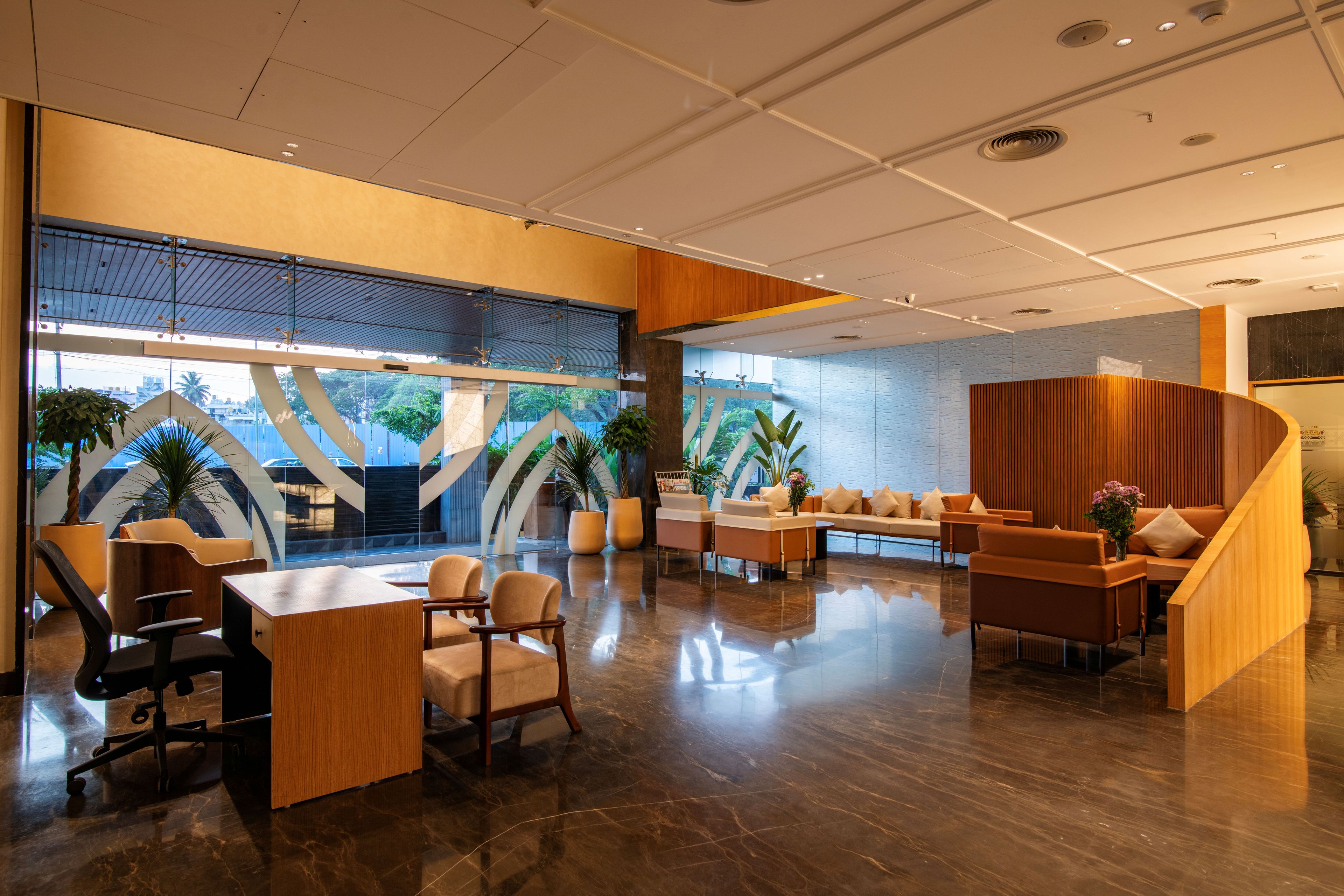 Um lobby moderno com balcão de atendimento, área de estar e escada para andares superiores.