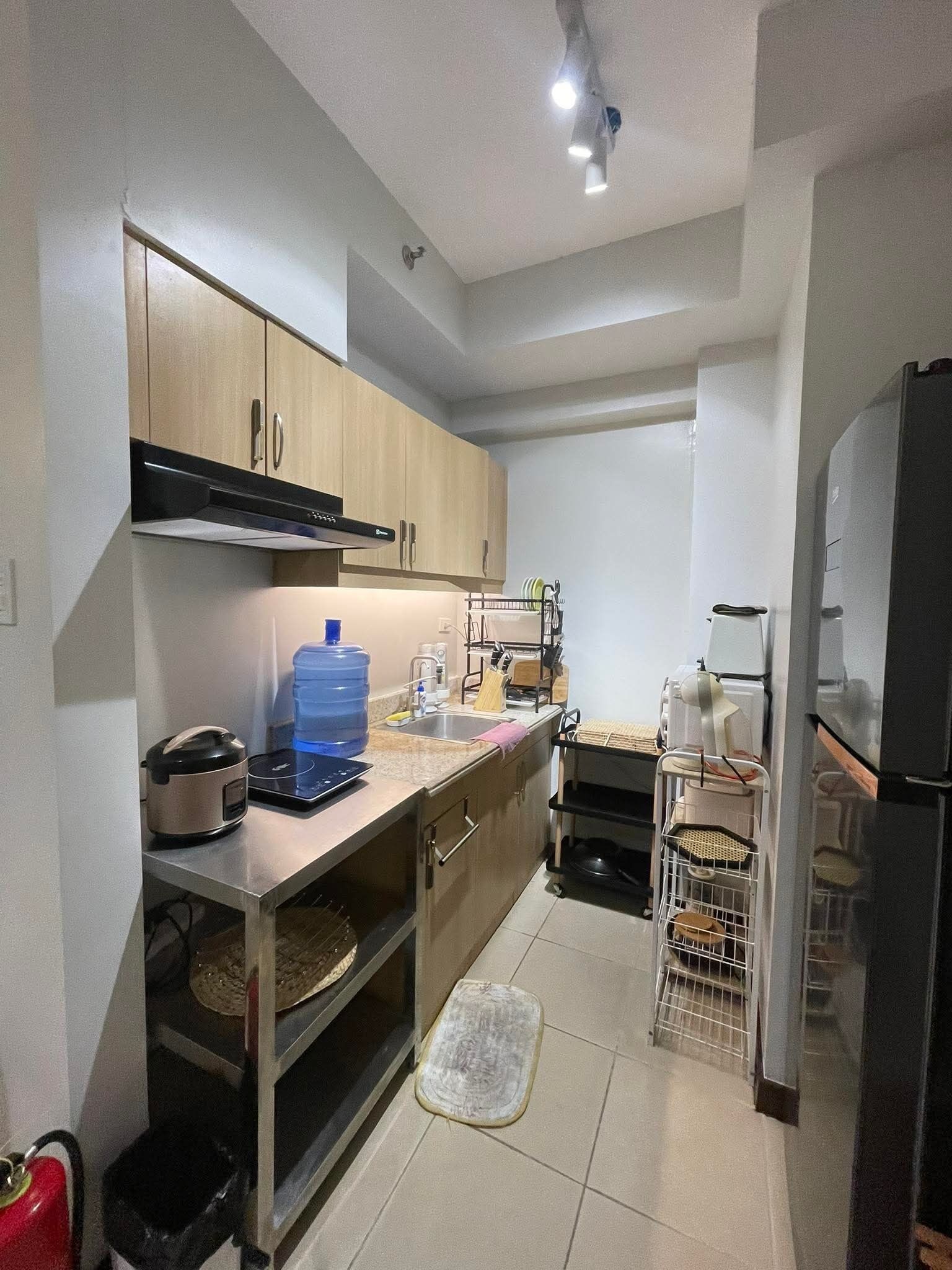 Uma cozinha compacta com armários de madeira, bancada de aço inoxidável e geladeira.