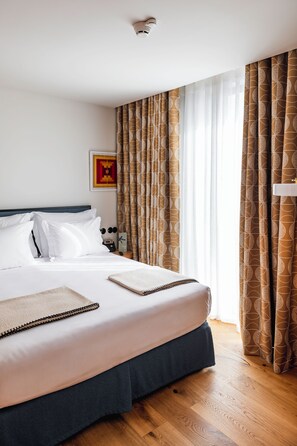 Quarto de hotel com cama, mesa de cabeceira, telefone e um quadro pendurado na parede.