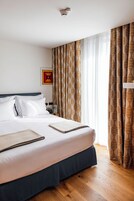 Quarto de hotel com cama, mesa de cabeceira, telefone e um quadro pendurado na parede.