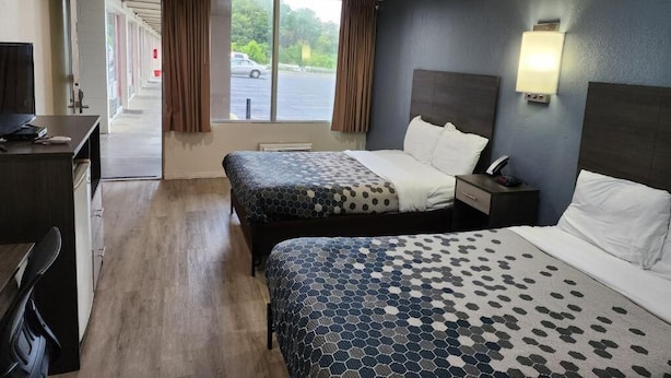 Quarto de hotel com duas camas, uma escrivaninha, uma cadeira e uma janela com cortinas.