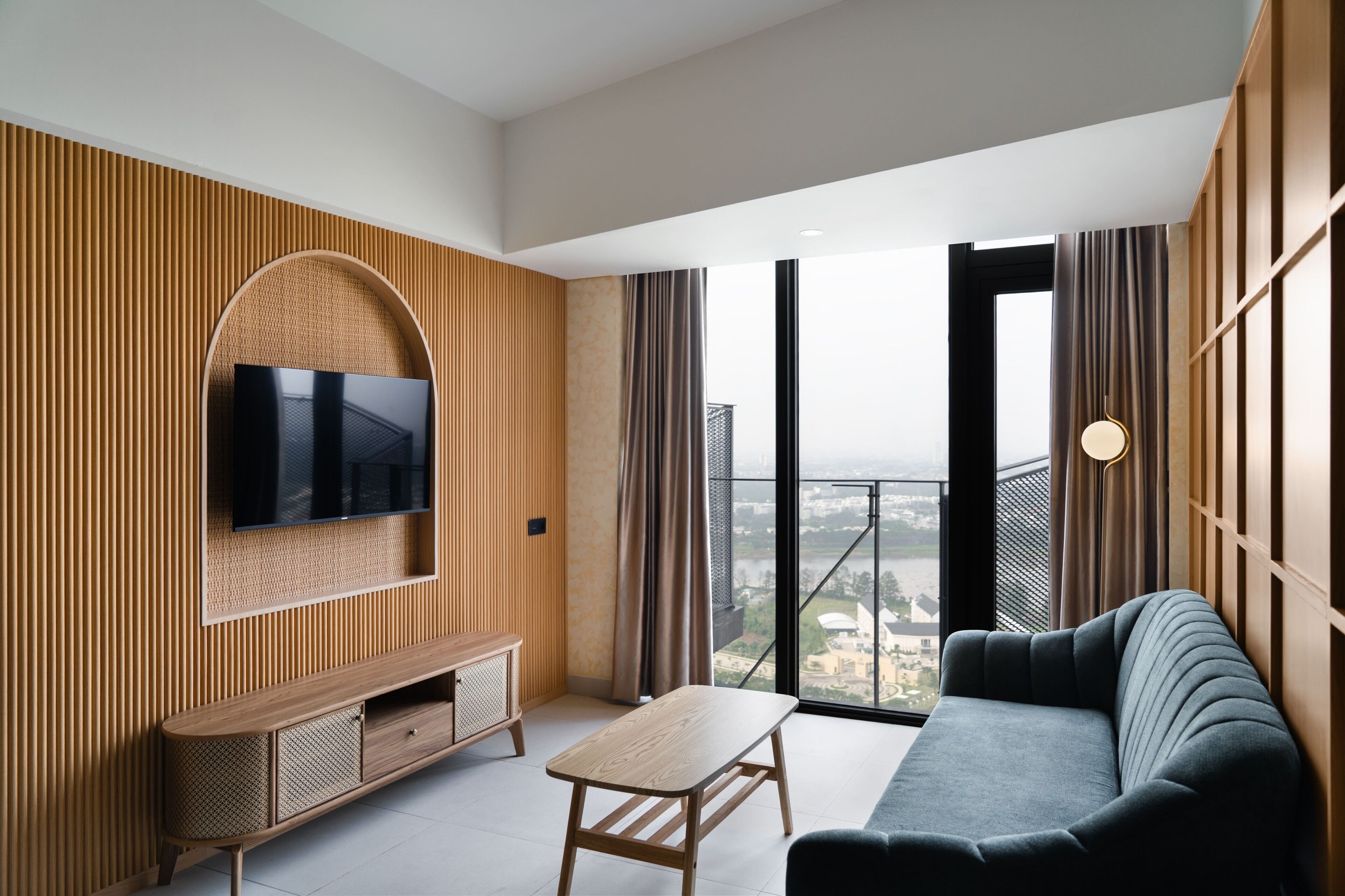Uma sala de estar moderna com televisão de tela plana, sofá, mesa de centro e vista da cidade por grandes janelas.