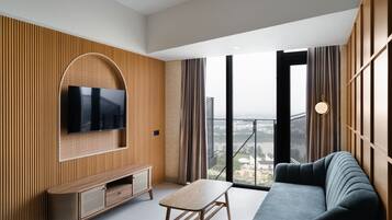 Uma sala de estar moderna com televisão de tela plana, sofá, mesa de centro e vista da cidade por grandes janelas.
