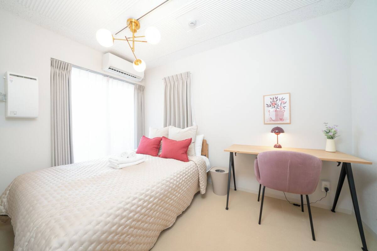 Quarto com cama, escrivaninha, cadeira, luminária e quadro na parede.