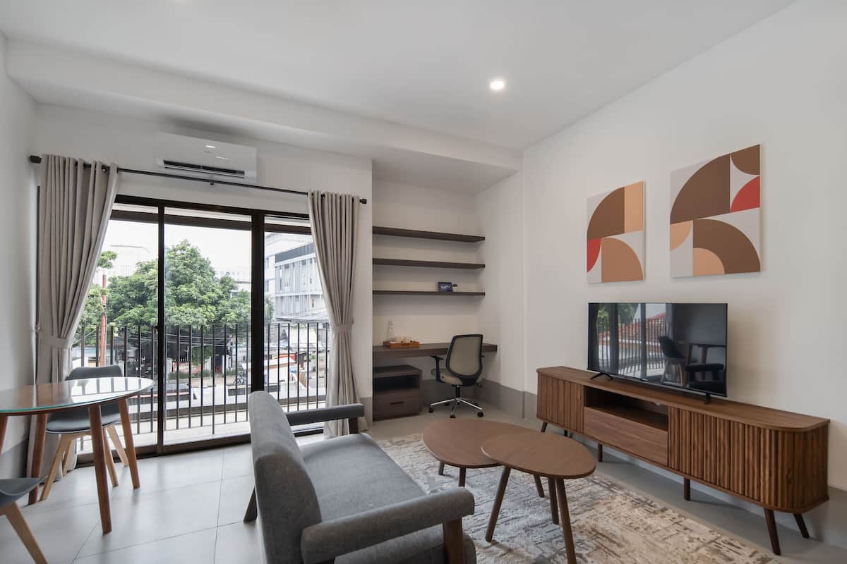 Uma sala de estar moderna com sofá, mesa de jantar, televisão e obras de arte.