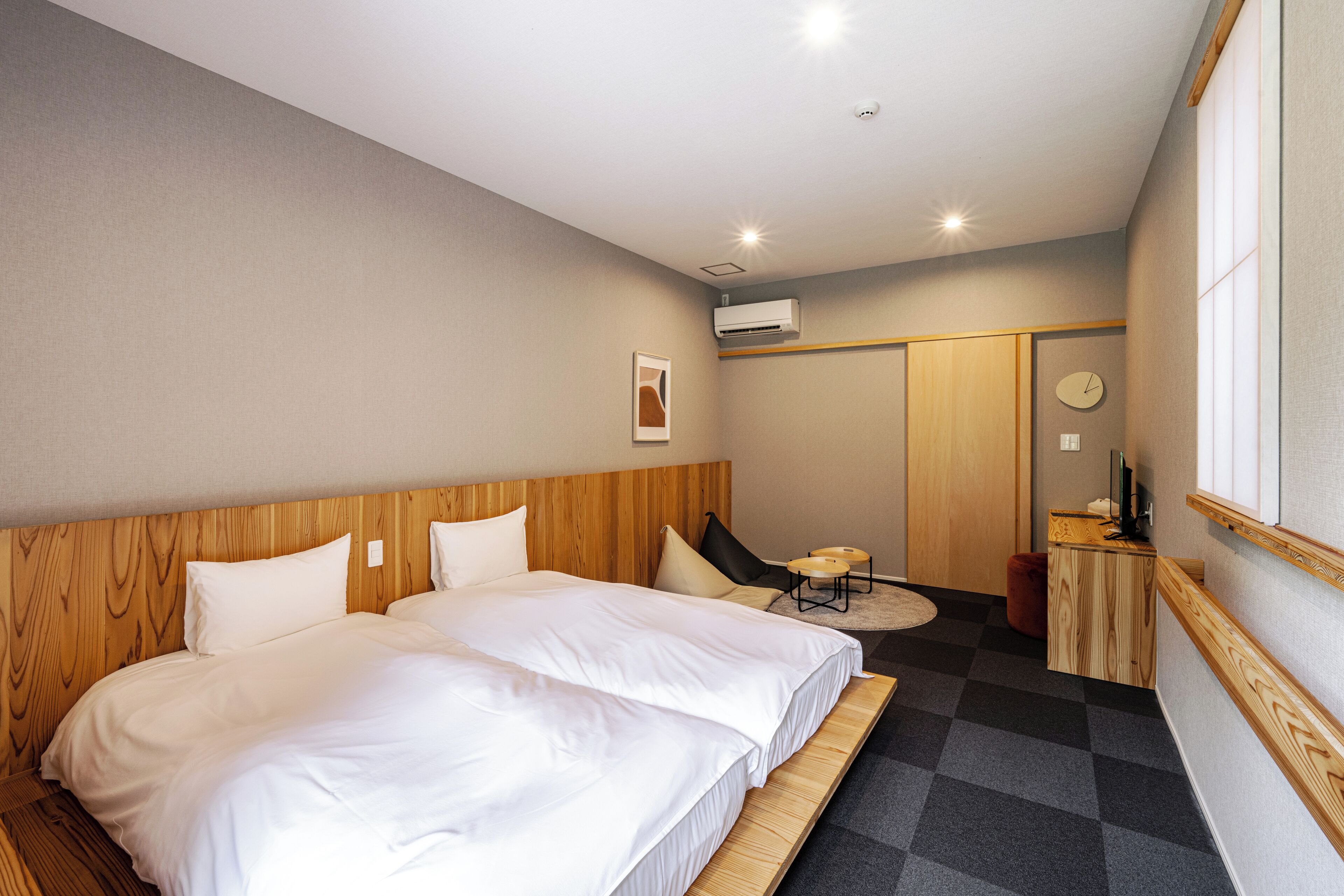 Quarto de hotel com uma cama grande, uma escrivaninha pequena, uma cadeira e uma mesa redonda.