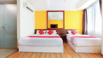 Quarto de hotel com duas camas, piso de madeira, um espelho e uma janela com cortinas.