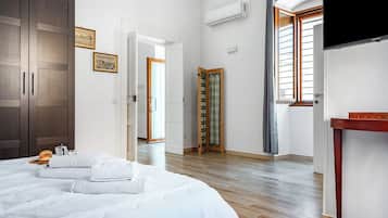 Quarto de hotel com cama, guarda-roupa, banheiro com cortina de chuveiro e ar condicionado.