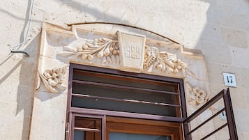 Fachada de edifício com uma janela grande, esculturas de pedra decorativas e uma porta.