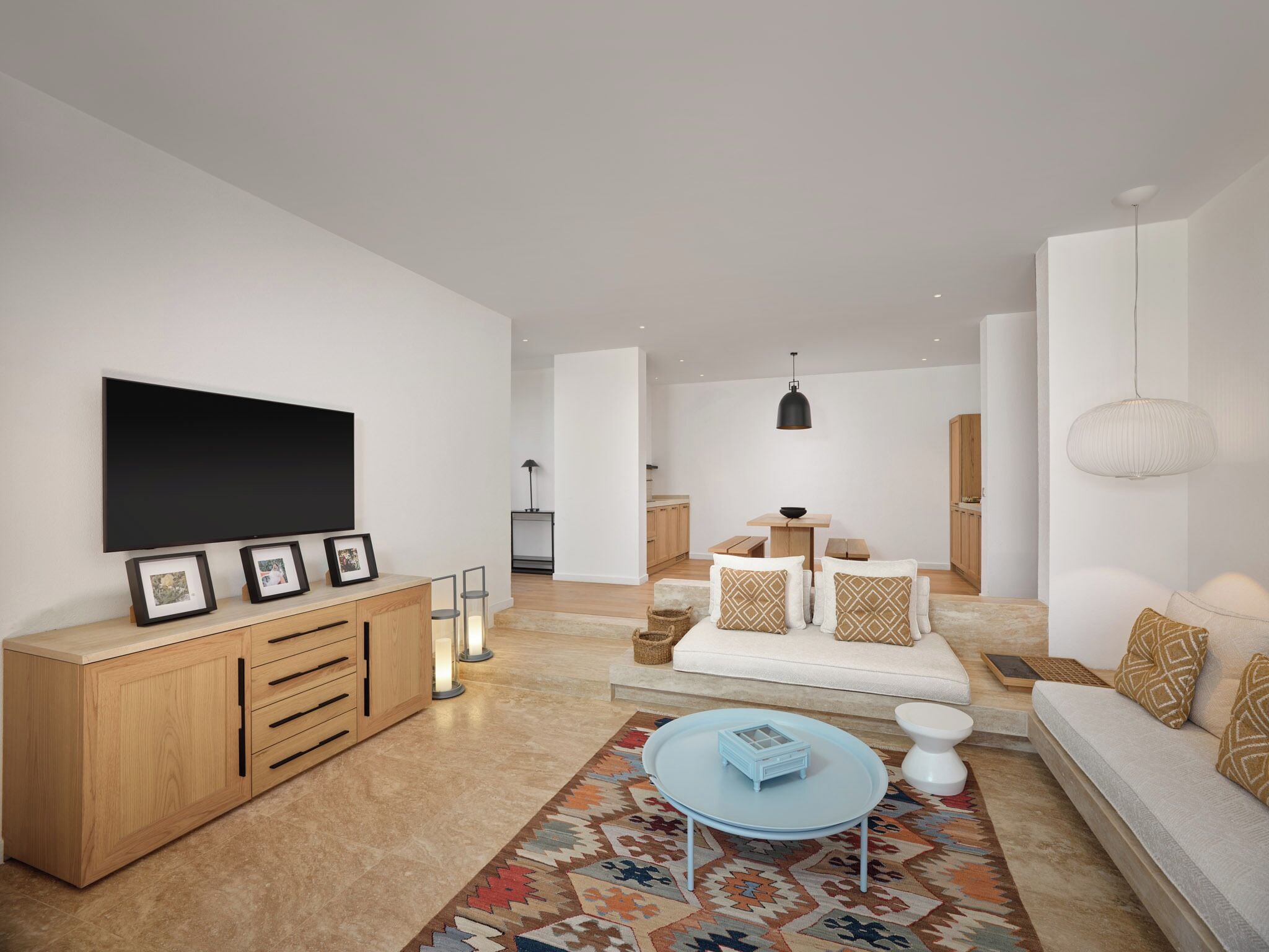 Uma sala de estar moderna com televisão de tela plana, aparador de madeira, sofá, mesa de centro e tapete estampado.