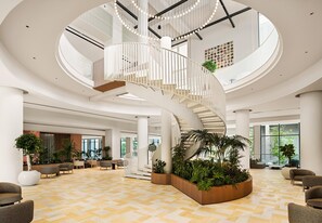 Um hall amplo com uma escadaria espiral central, áreas de estar e grandes janelas.