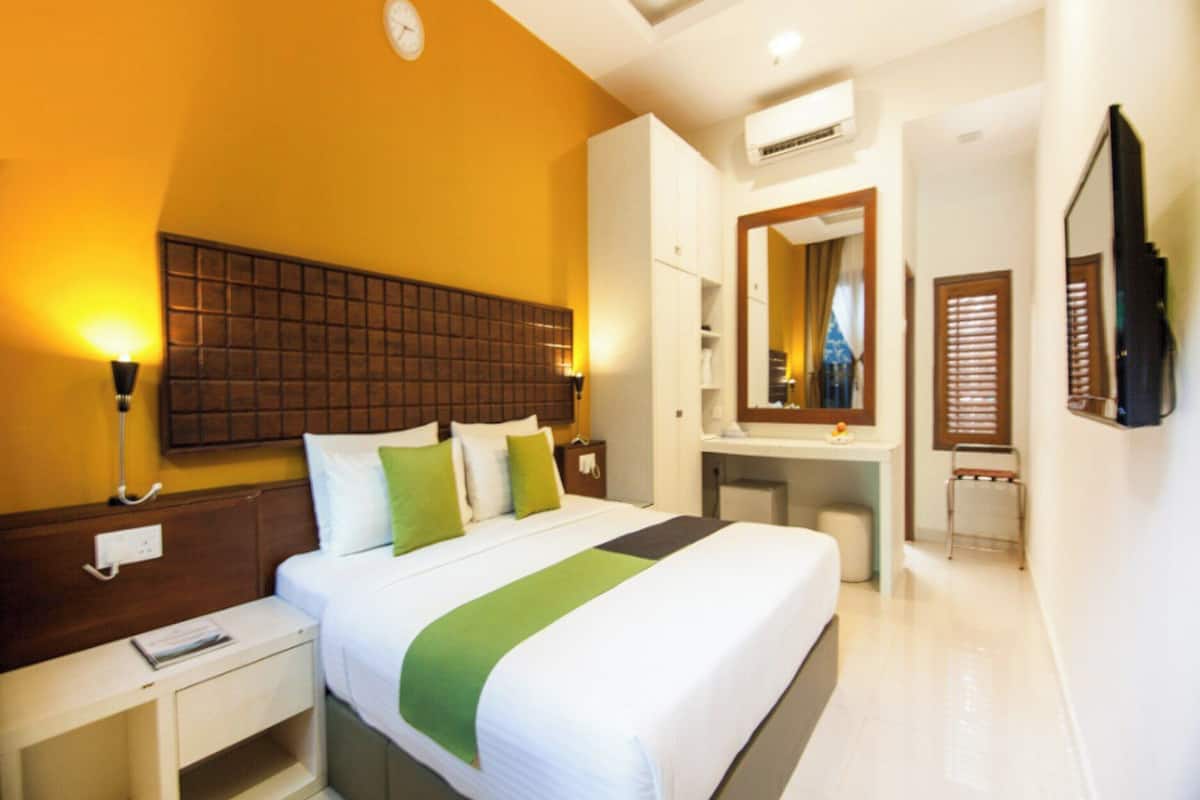 Quarto de hotel com uma cama grande, mesa de cabeceira, espelho, ar condicionado e televisão.