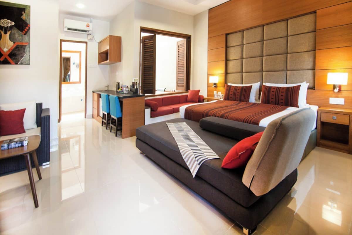 Quarto de hotel moderno com uma cama grande, um sofá, uma escrivaninha e um espaço de jantar.