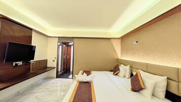 Quarto de hotel com cama, televisão, banheiro e corredor.