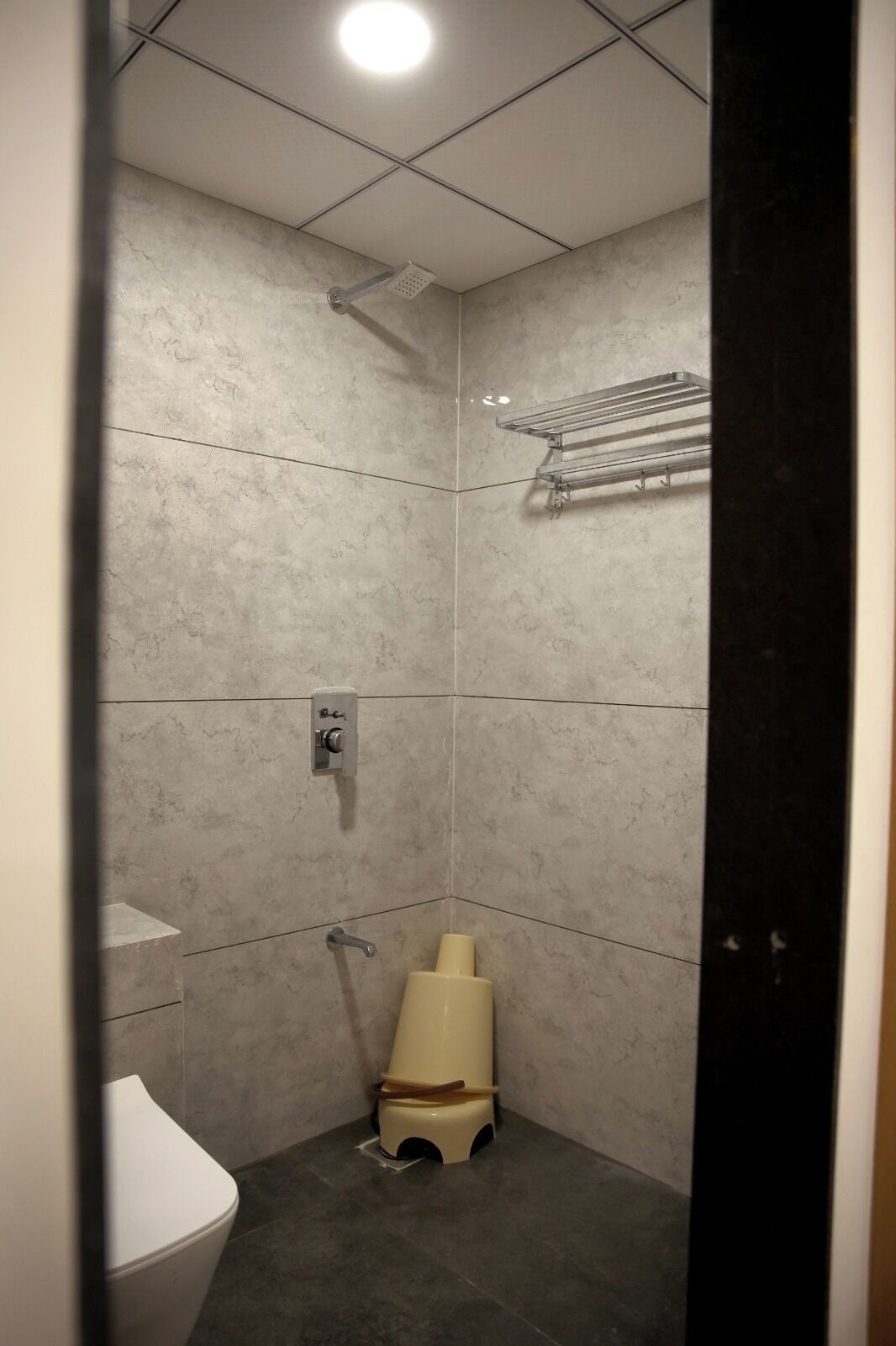 Um banheiro pequeno e moderno, com chuveiro, vaso sanitário e porta-toalhas.