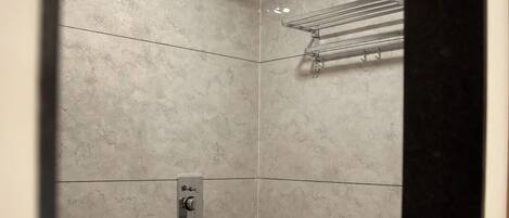 Um banheiro pequeno e moderno, com chuveiro, vaso sanitário e porta-toalhas.