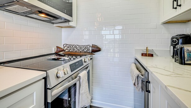 Uma cozinha moderna com azulejos brancos tipo metrô, eletrodomésticos de aço inoxidável e bancada de mármore.