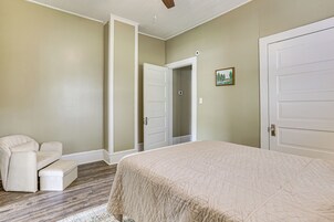 Quarto com cama, cadeira e duas portas.