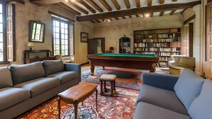 Uma sala de estar acolhedora com mesa de bilhar, sofás e estante de livros.
