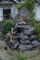 Um jardim com paisagismo, apresentando uma estrutura de pedra, rodeado por vegetação e plantas.