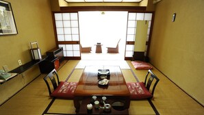 Um quarto em estilo japonês tradicional com tatames, uma mesa baixa com jogos de chá e portas deslizantes que dão para uma área externa.