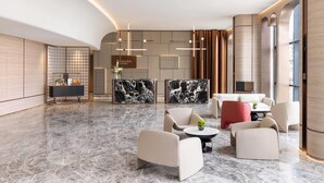 Um lobby moderno com piso de mármore, áreas de estar e um balcão de recepção.