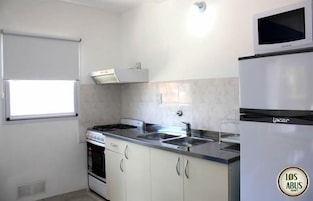 Cozinha equipada com fogão a gás, micro-ondas, frigorífico e janela.